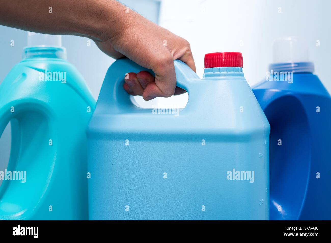 The hand is holding a blue container of cleaner Stock Photo - Alamy