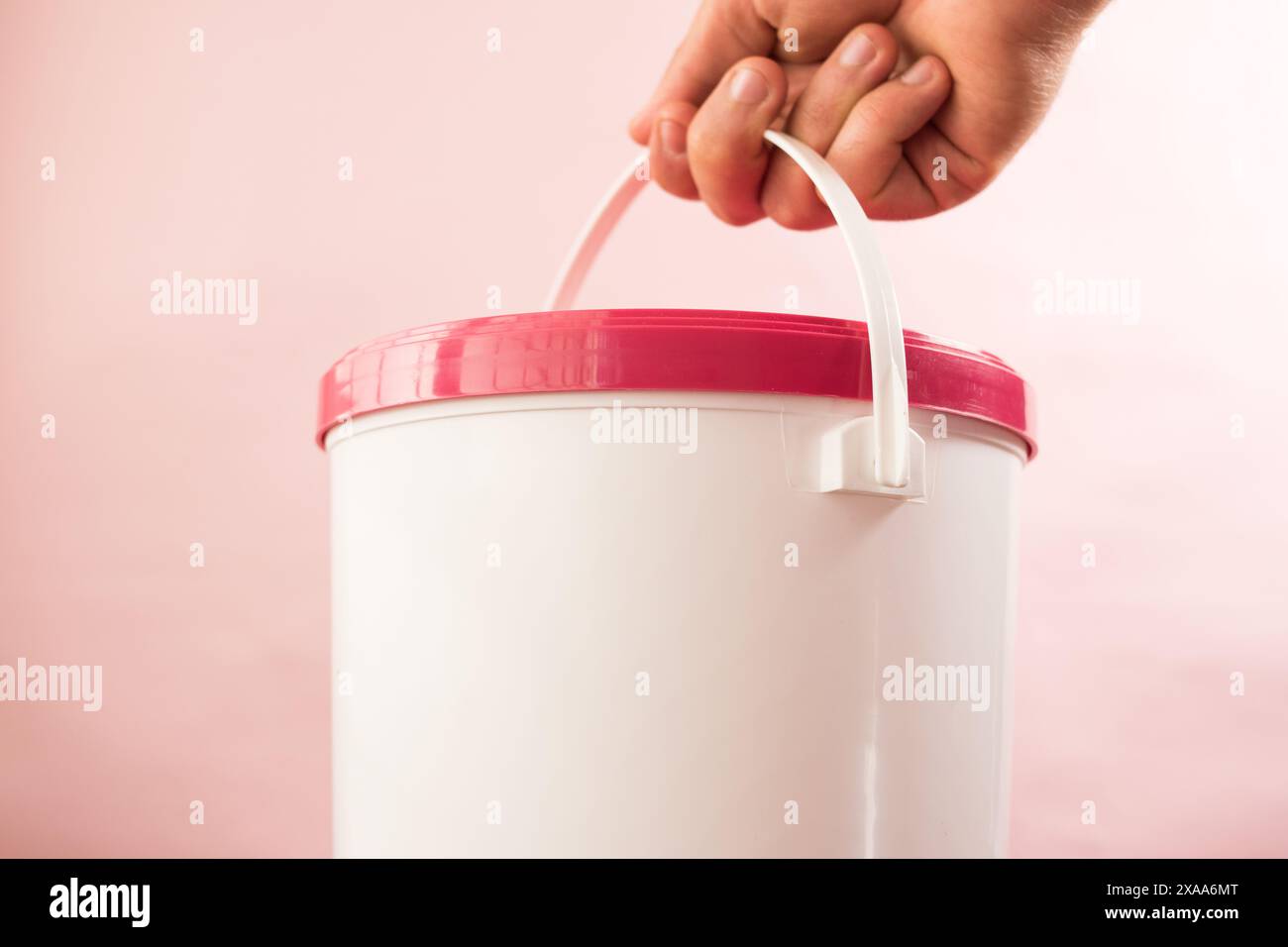 A hand holding a white plastic bucket with a red lid Stock Photo - Alamy