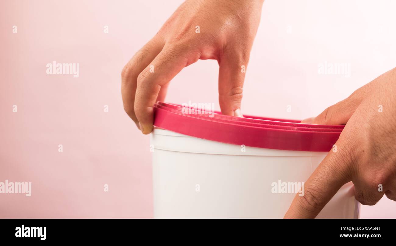 The man removing the plastic lid on a white bucket Stock Photo - Alamy