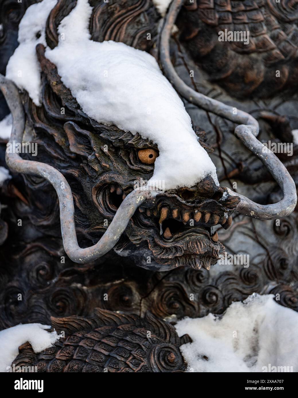 A menacing dragon statue covered in snow at the ancient sacred ...