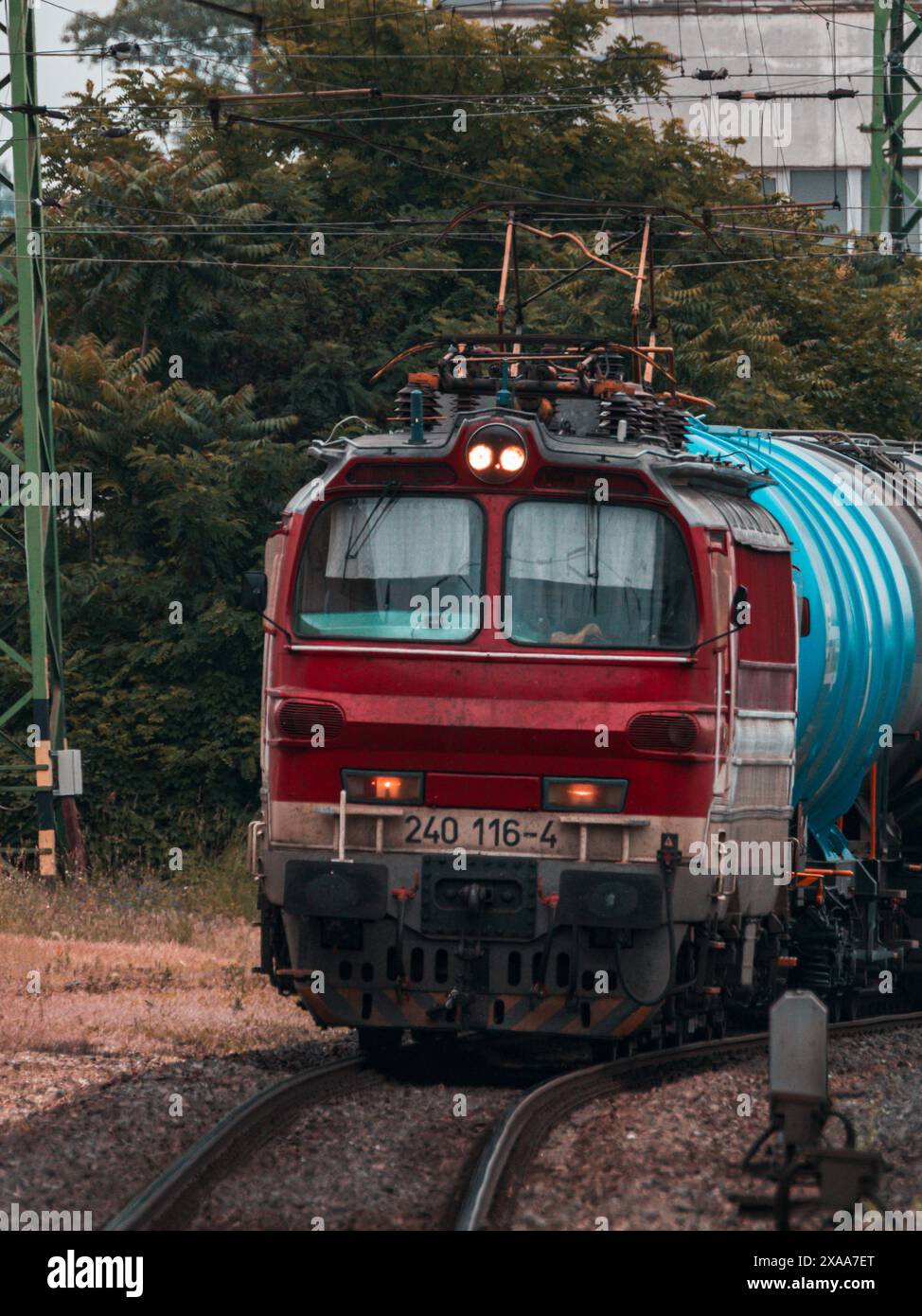 The red locomotive is moving along the curved railway tracks, pulling ...