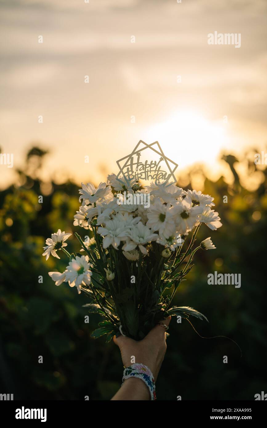 A bouquet of white flowers with 'happy birthday' sign in a field in ...