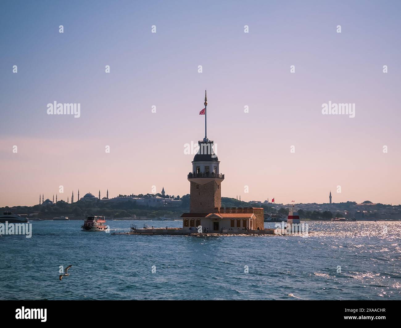 A lighthouse standing amidst a cluster of boats on the water's edge ...