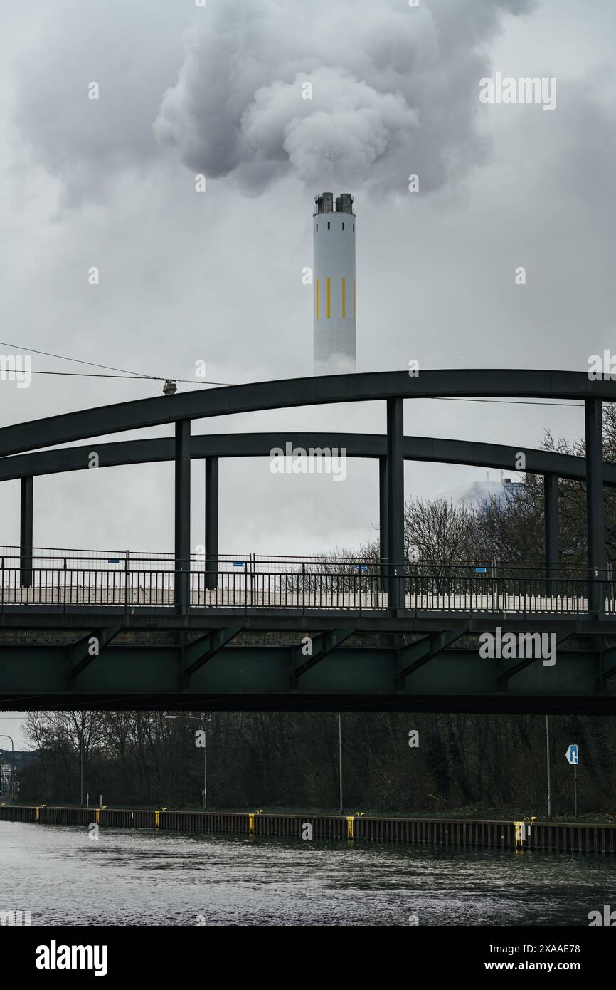 The white smoke billows from a pipe tower with a bridge in the ...