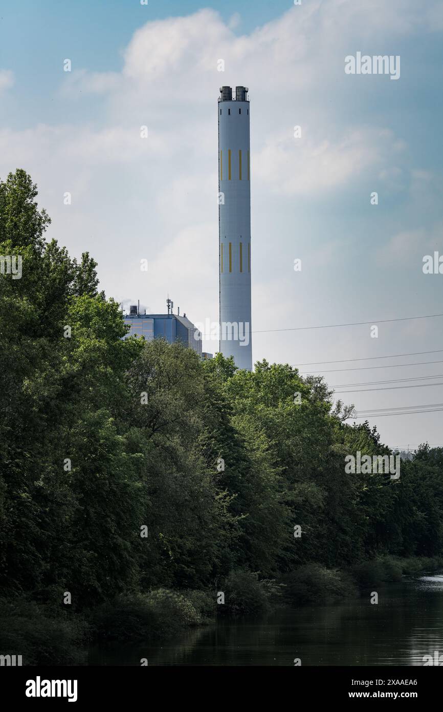 A tall industrial tower on the riverbank surrounded by trees Stock ...