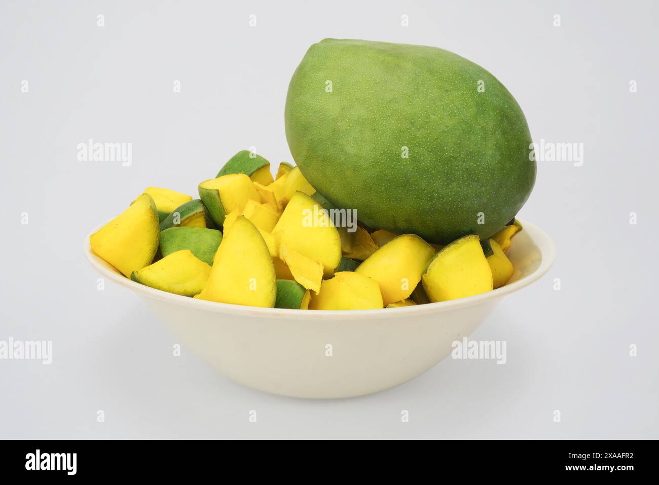 side view of mango slices with a large mango in a big white bowl ...
