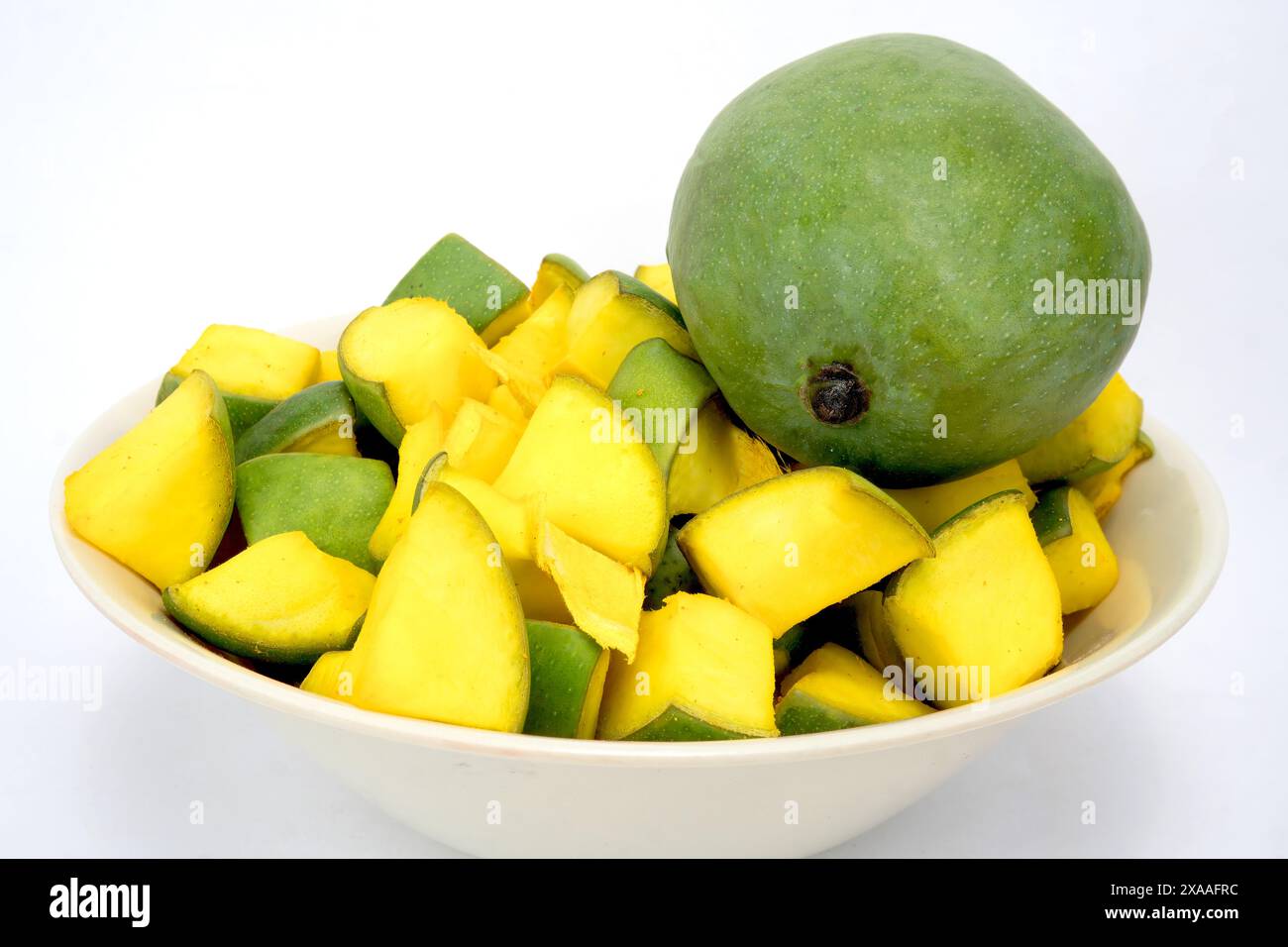very close-up view of mango slices with a large mango in a big white ...