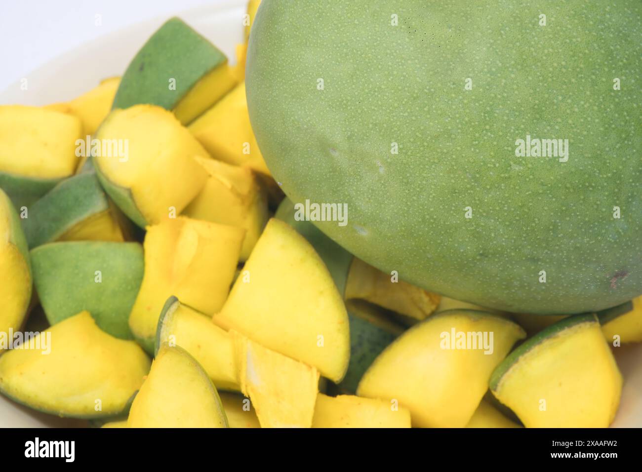 A close-up view of mango slices with a large mango, prepared for making ...