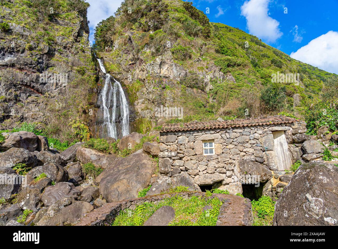 Waterfall and small rustic house next to the Fajã dos Bodes waterfall ...