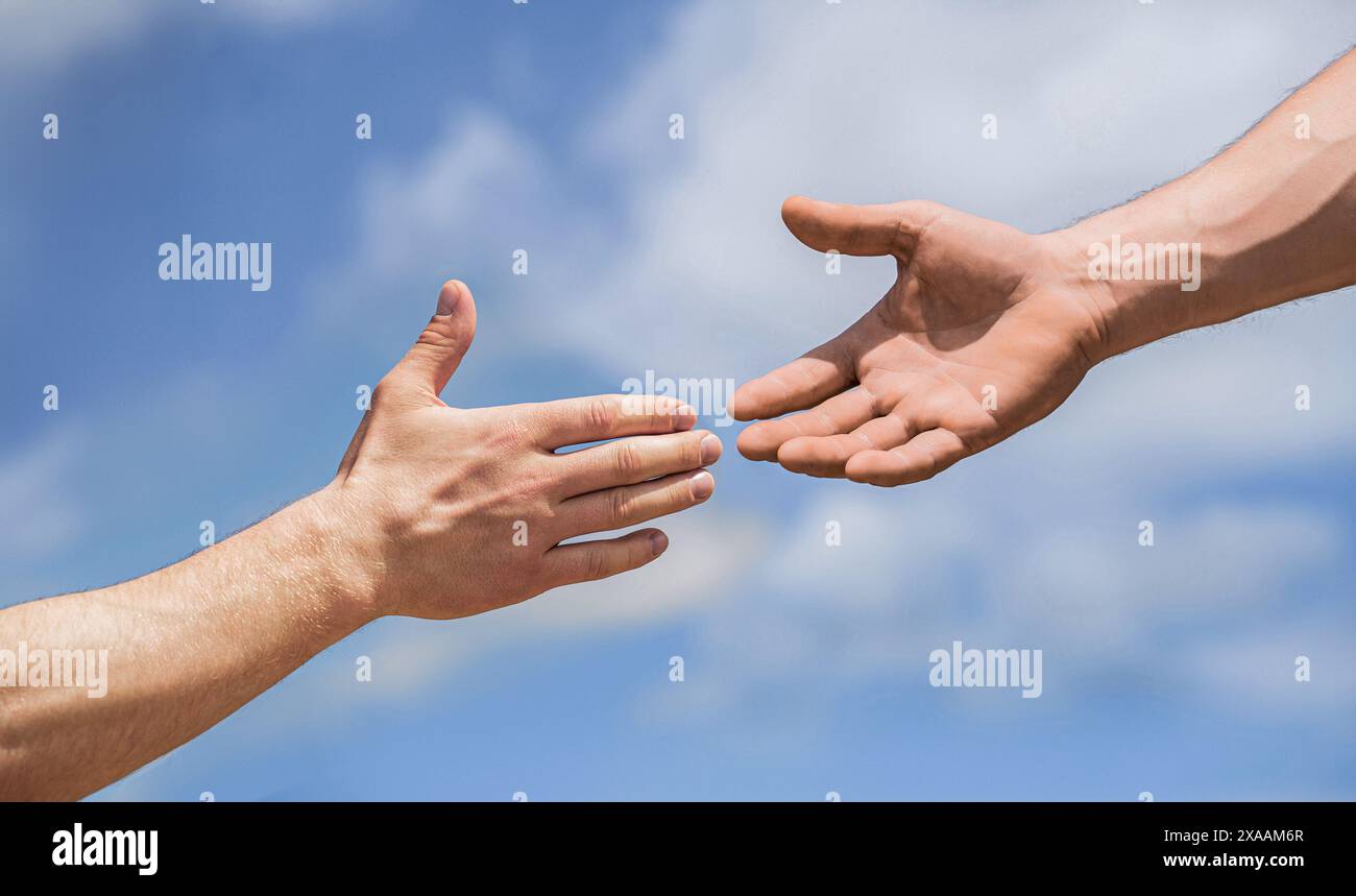Two male hands reaching towards each other on isolated sky background ...