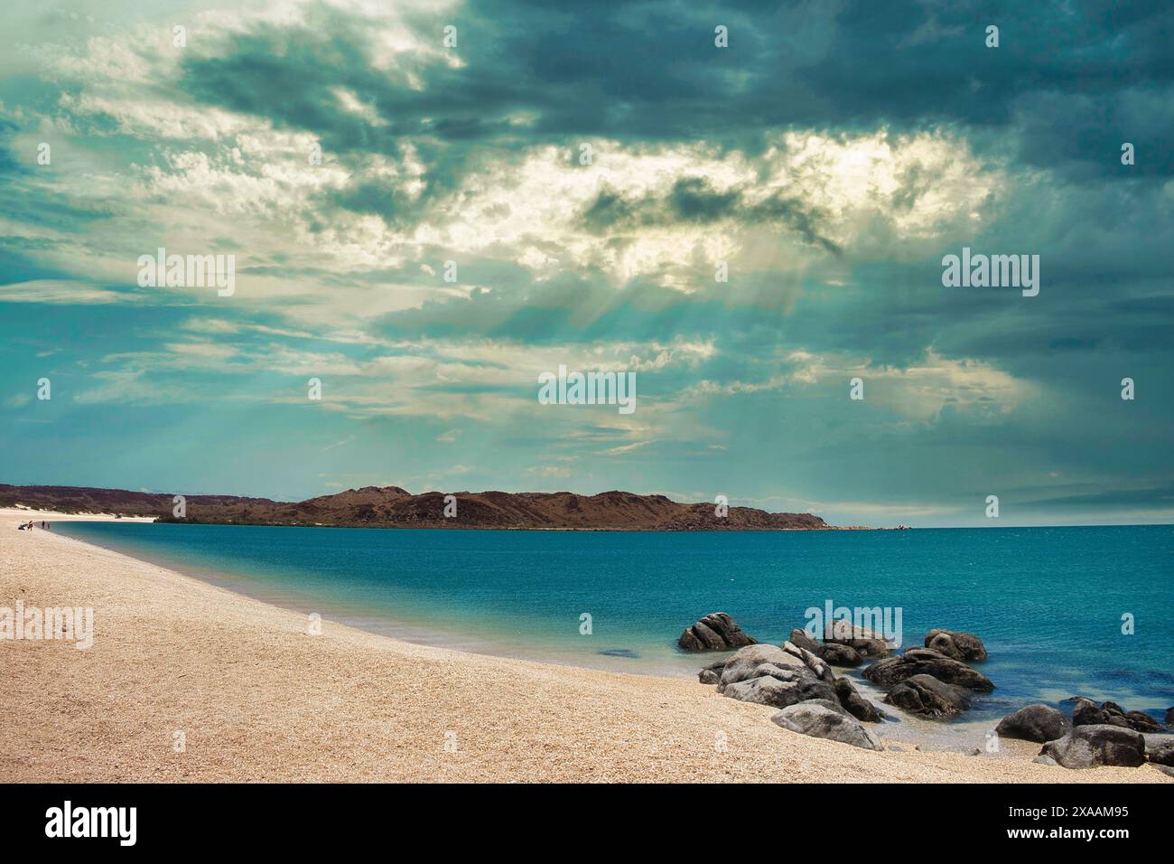 Dramatic sky with sunrays shining through dark clouds above the beach ...