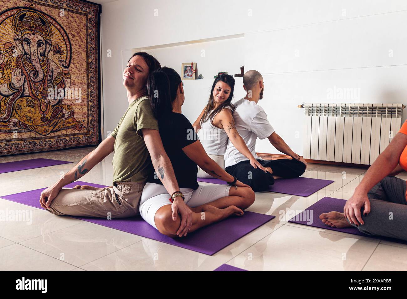 Group of people in a Yoga class doing postures in pairs while sitting ...