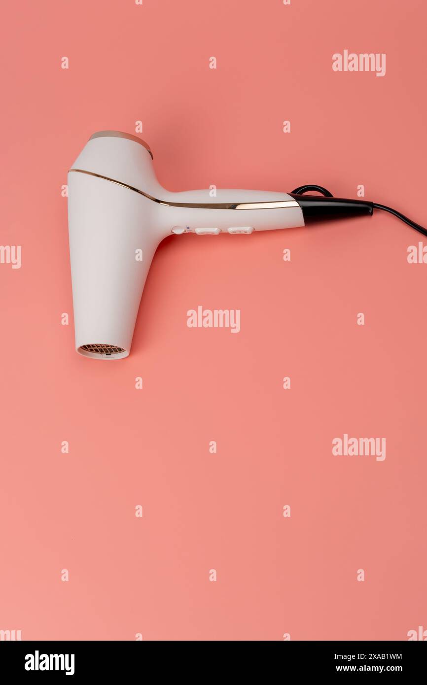 Hair dryer for drying hair on a pink background. The buttons are ...
