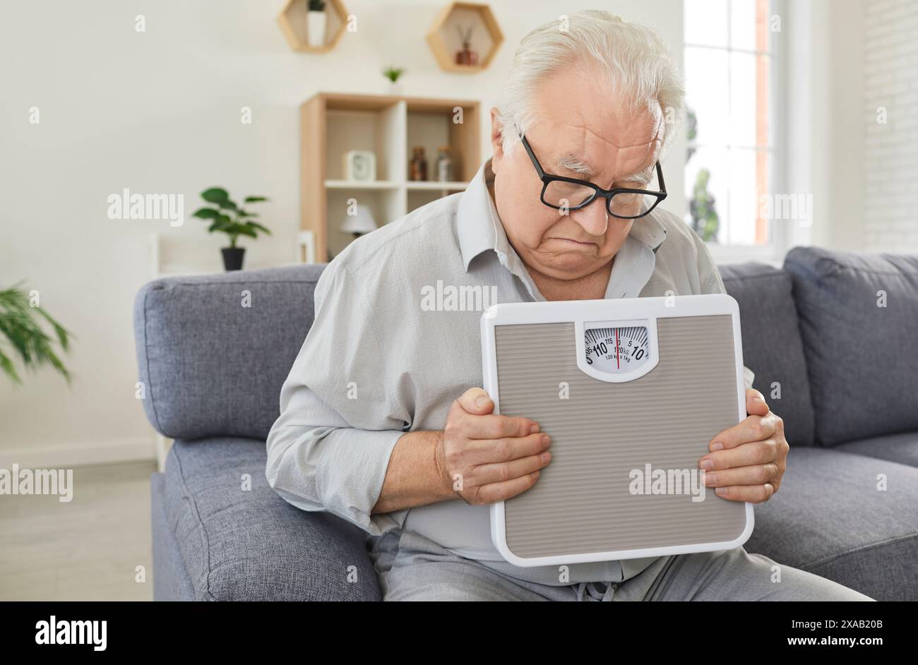 Upset senior man holding scales with frustrated face sitting in the ...