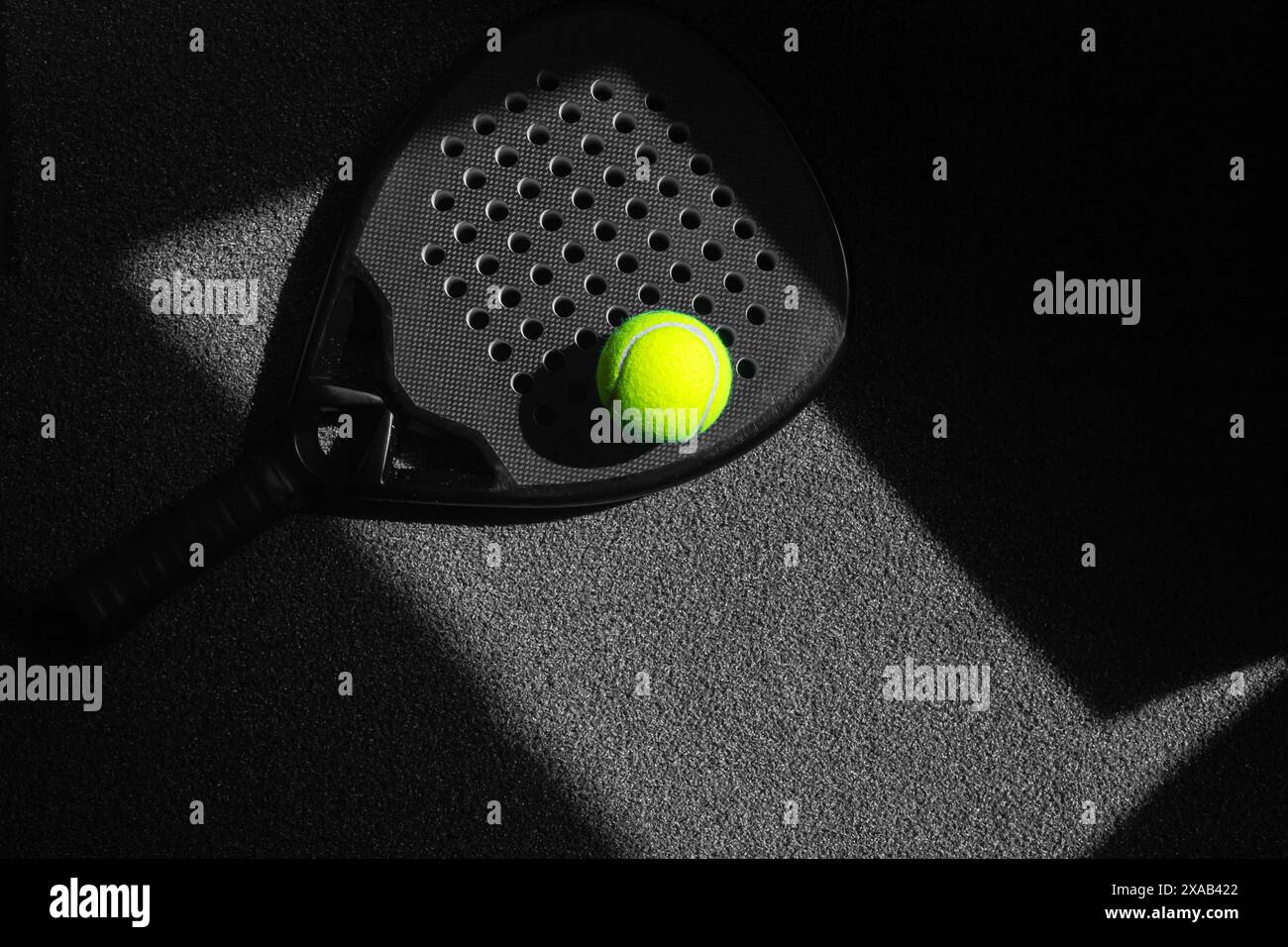 Black professional paddle tennis racket and ball with natural lighting ...