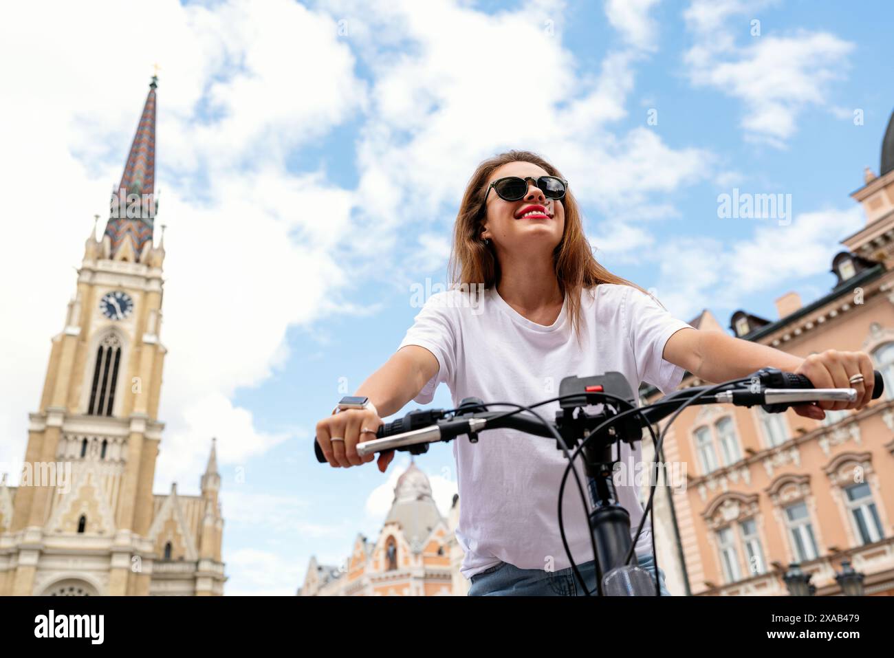 Low angle view woman riding a bicycle along the street of a European ...