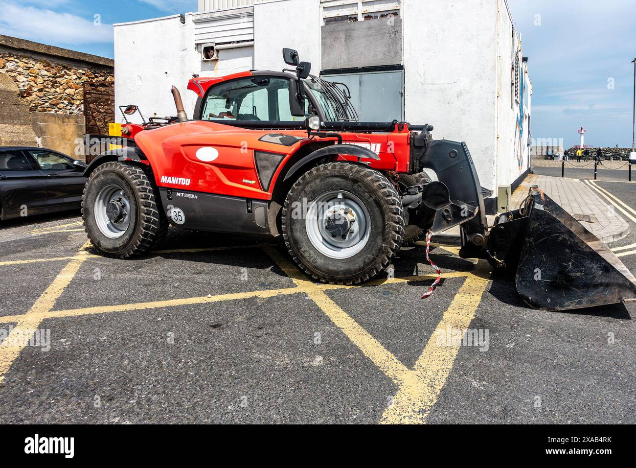 A red Manitou telehandler parked near a building on the pier in Howth ...