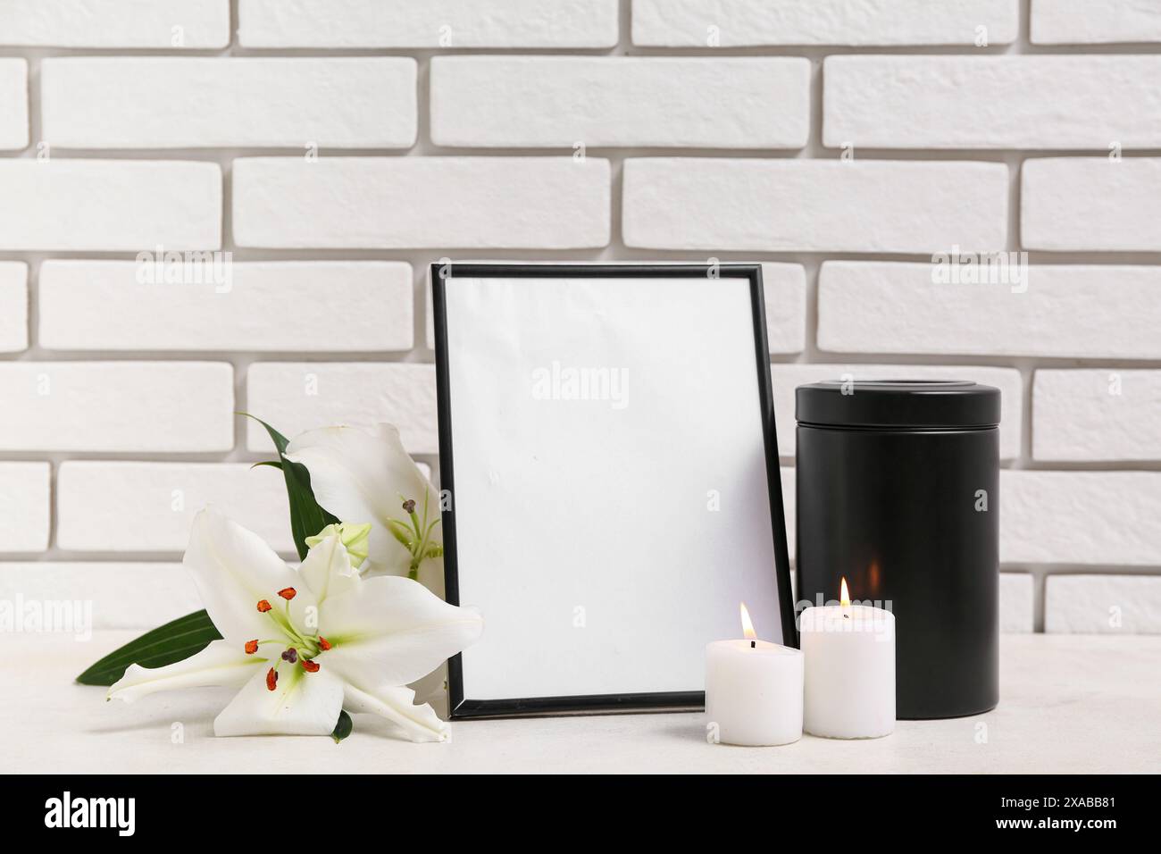 Blank funeral photo frame, mortuary urn, candles and flowers on white ...