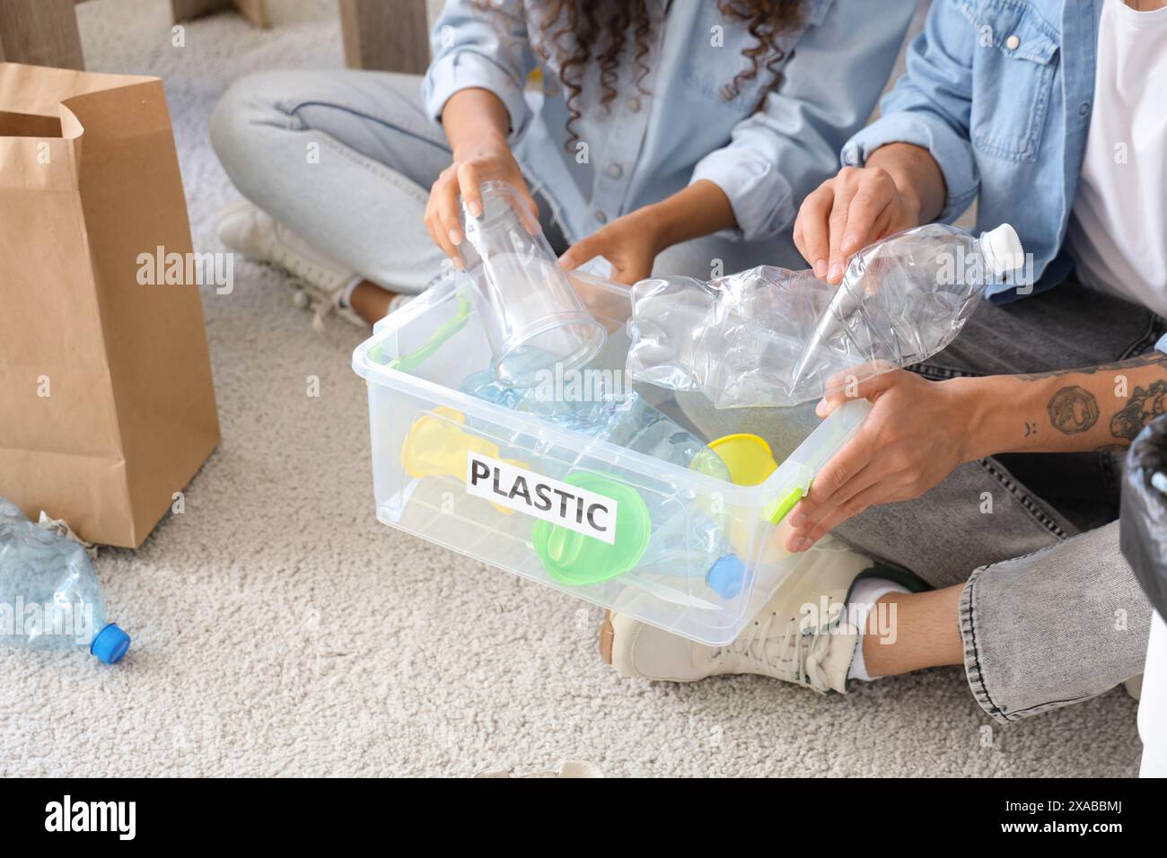 Young couple throwing plastic rubbish in garbage container at home ...