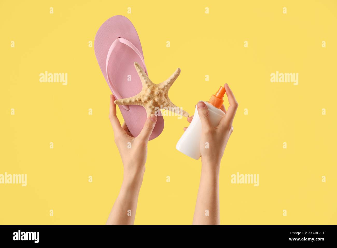 Female hands with flip-flop, sunscreen cream and starfish on yellow ...