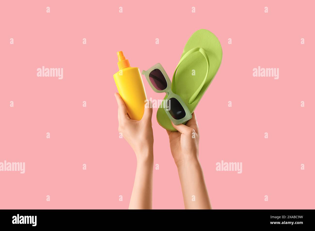 Female hands with flip-flop, sunscreen cream and sunglasses on pink ...