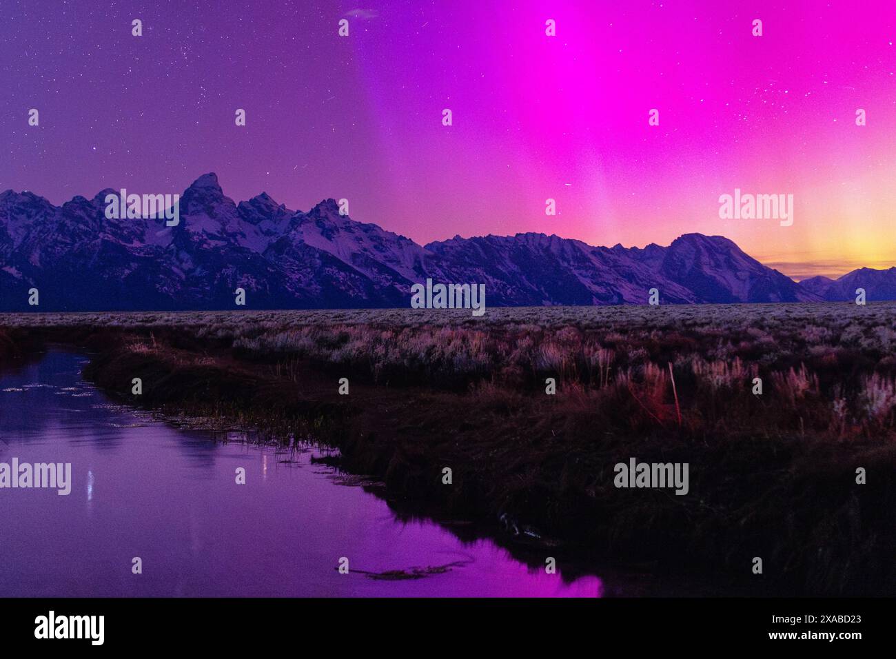 The aurora borealis shining brightly above the Teton Mountains and a ...