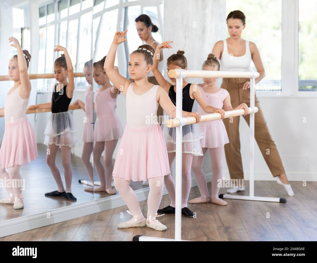 Teacher conducts class with children girls in ballet studio, observes ...