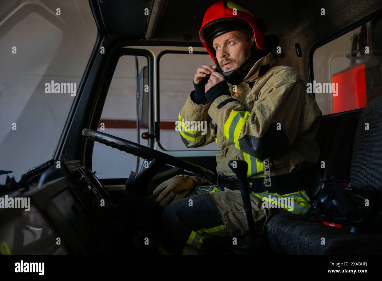 Firefighter in uniform wearing helmet inside fire truck Stock Photo - Alamy