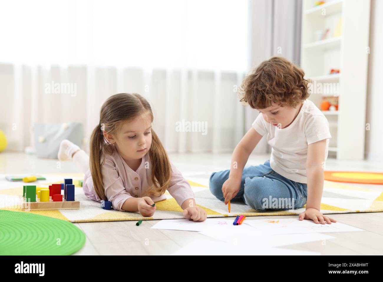 Cute little children drawing on floor in kindergarten Stock Photo - Alamy