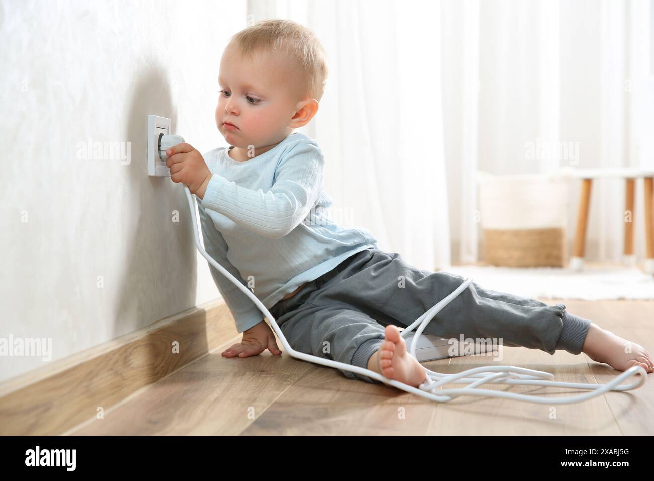 Little child playing with electrical socket and plug at home. Dangerous ...
