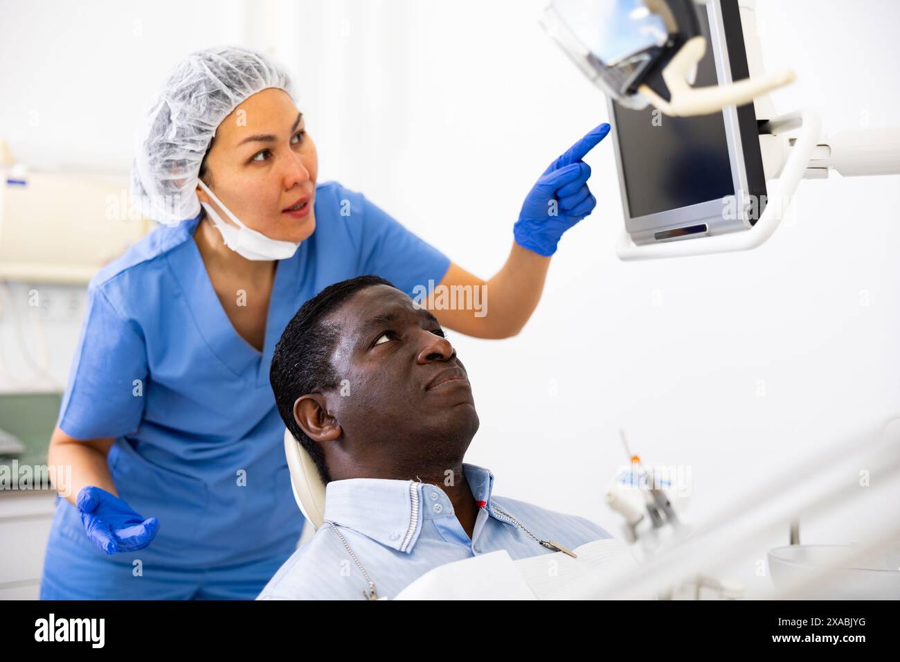Female stomatologist showing teeth radiography result on computer to ...