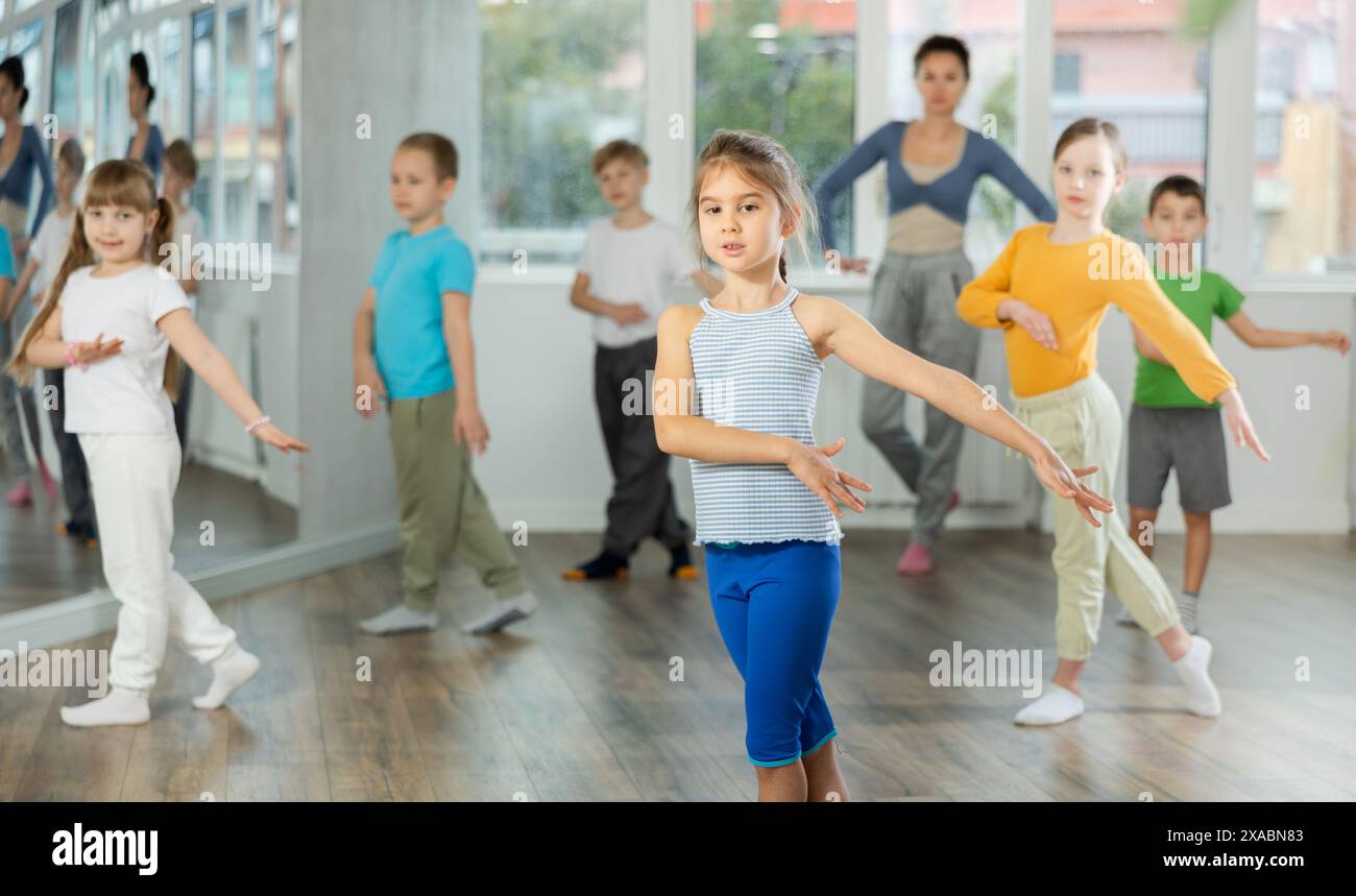 Children training modern dance moves together in studio under the ...