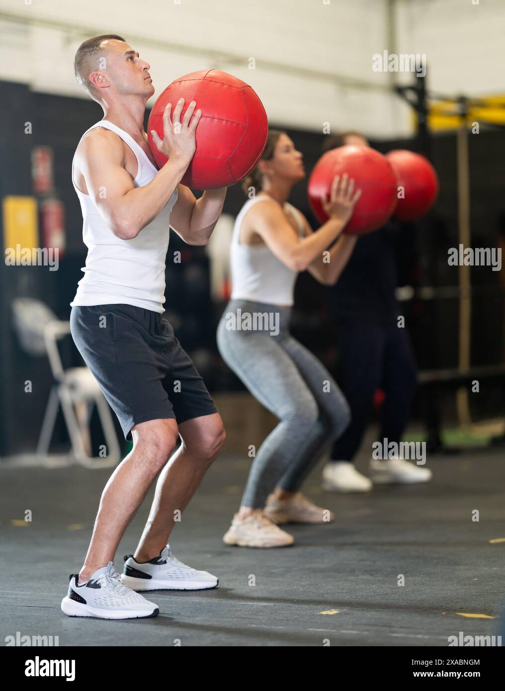 Sportive young guy working out with medicine ball in gym during ...
