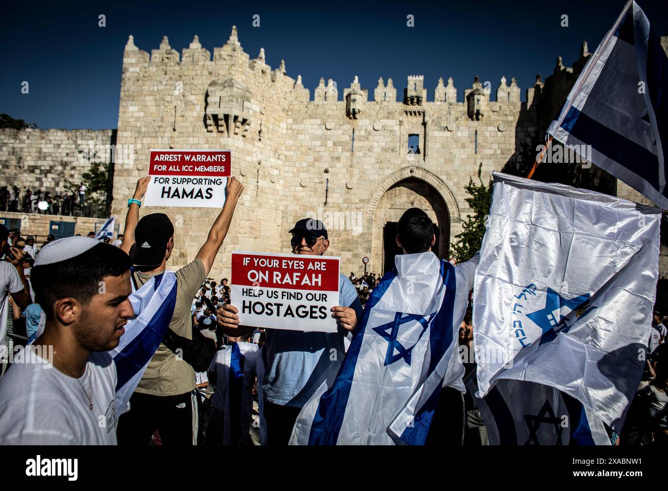 An Israeli man holds a poster as he stands next to youth draped in the ...