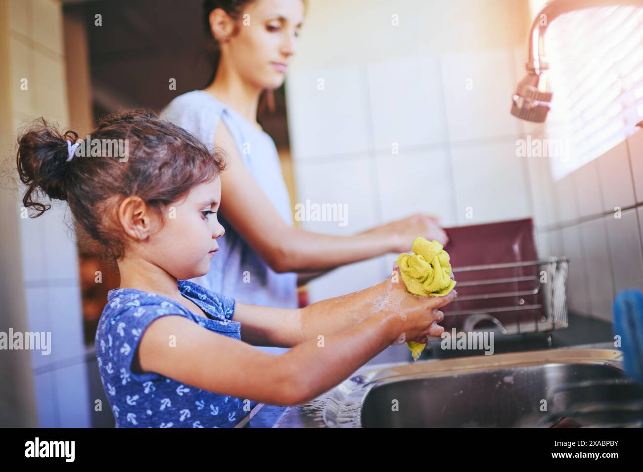 Mom, child and wash cloth with learning in kitchen with cleaning ...
