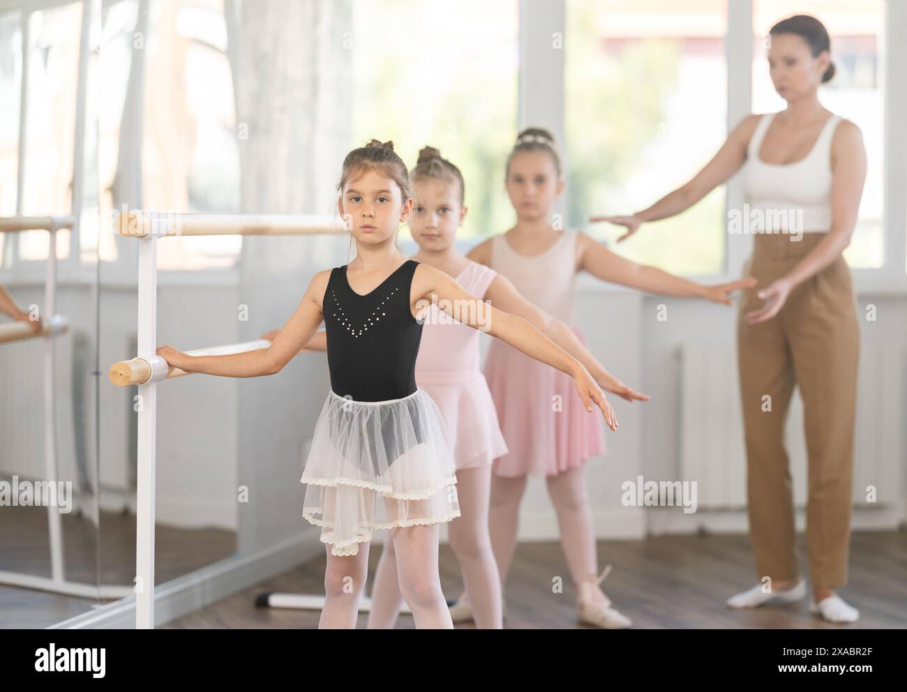 Woman teacher corrects group of girls in second position Stock Photo ...