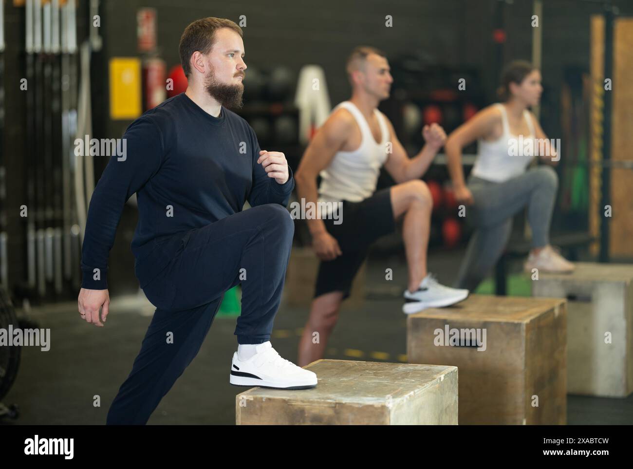 Sportive young guy doing step-up exercises with box during crossfit ...
