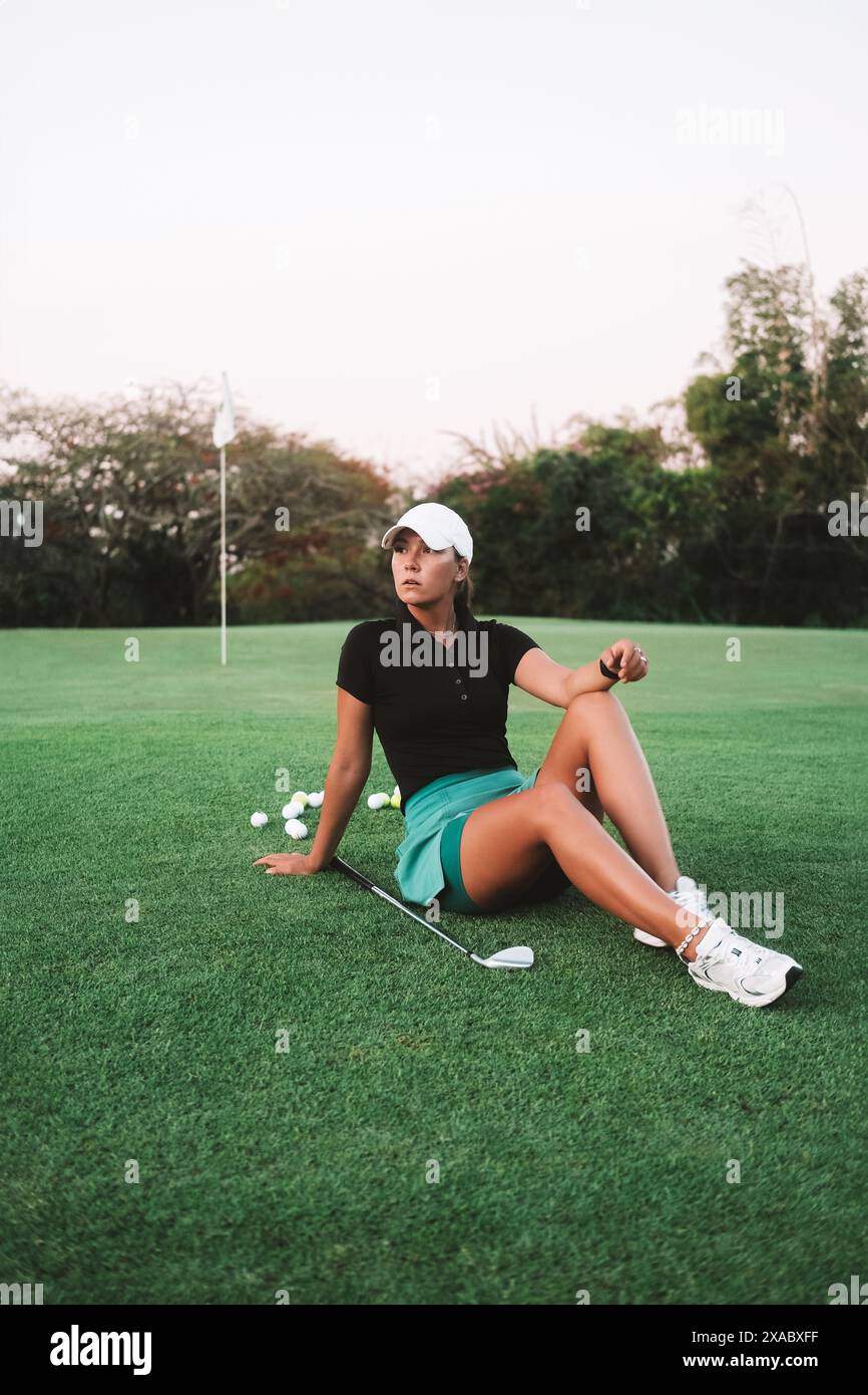 Young attractive woman sitting on the golf course at a country club and ...