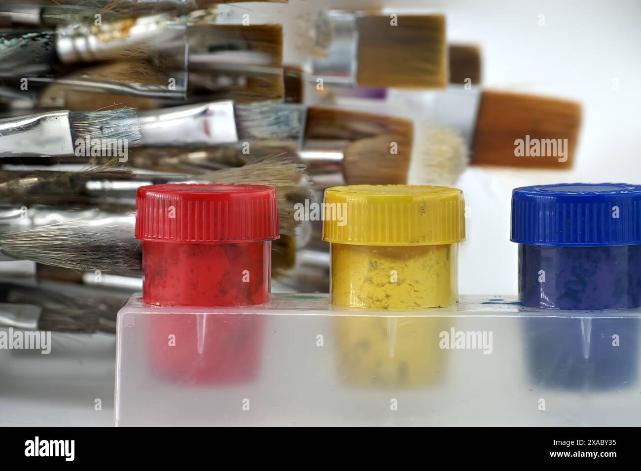 Array of paintbrushes of different sizes and colors alongside cans of ...