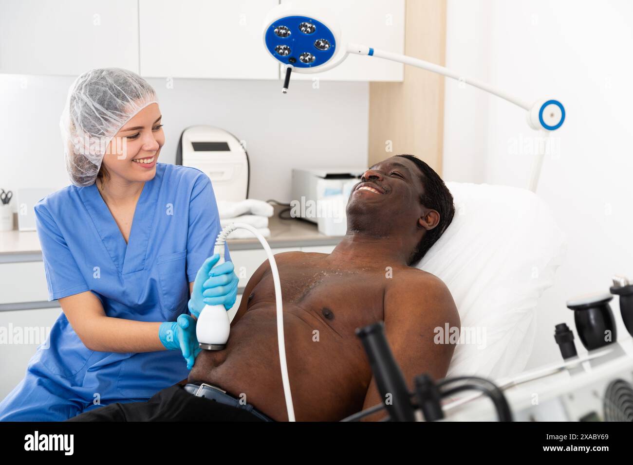 Cosmetologist performing ultrasound cavitation body procedure for man ...