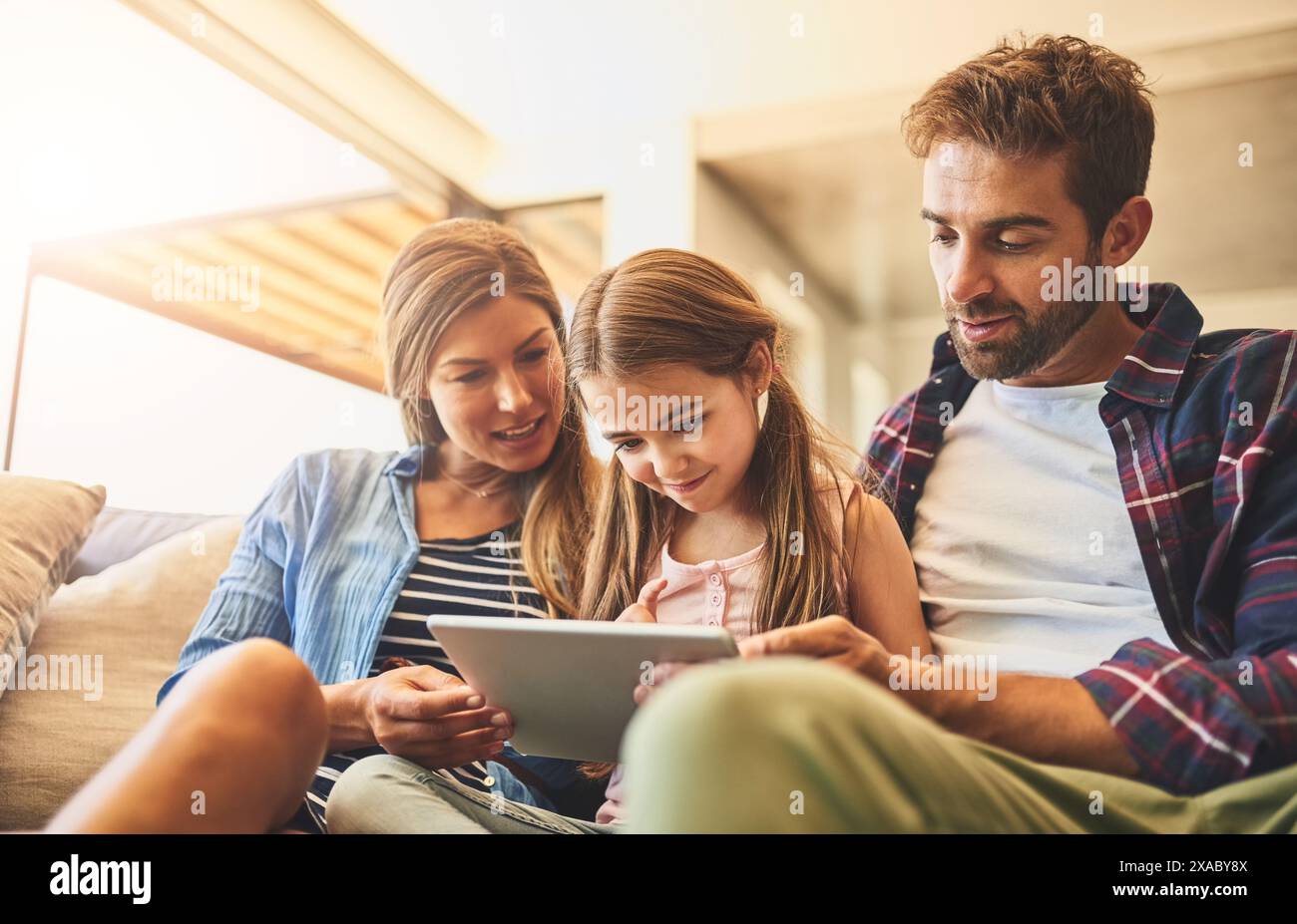 Happy, tablet and family hug on sofa with child, elearning and ...