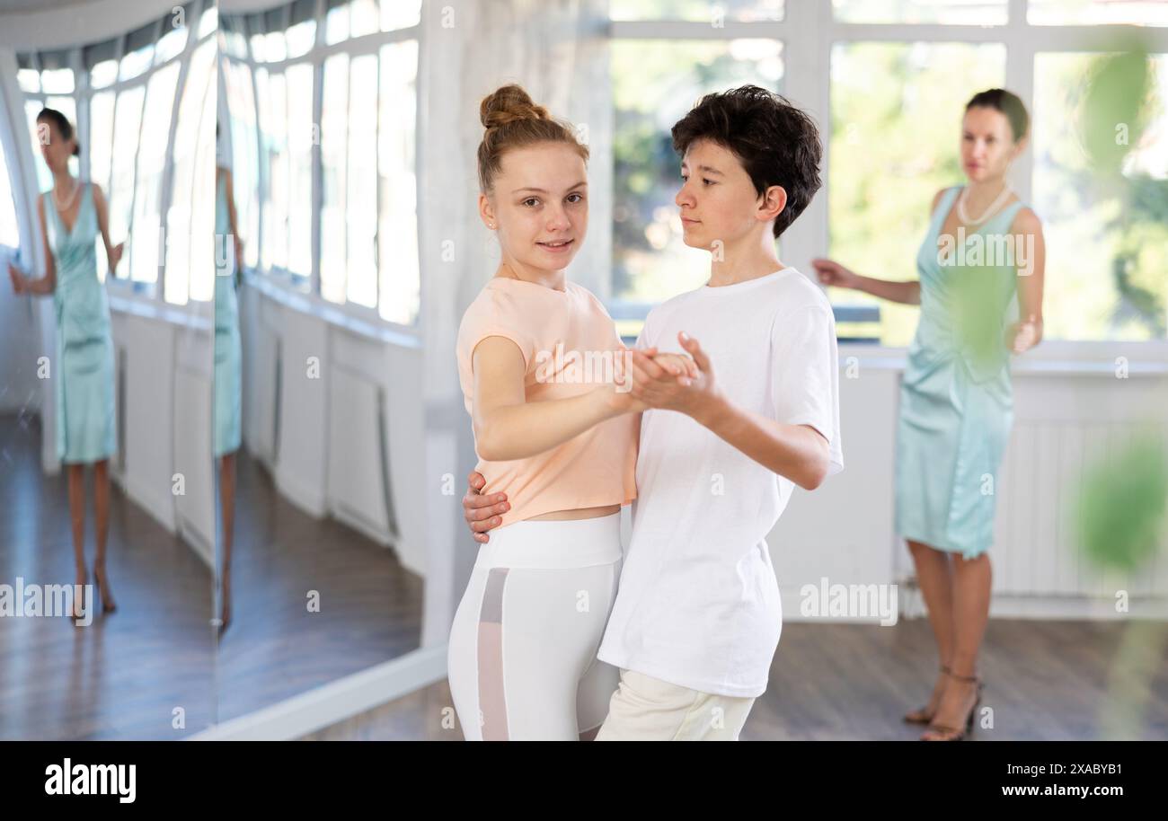 Dance lesson - teacher teaches teenage girl and boy to dance tango in ...