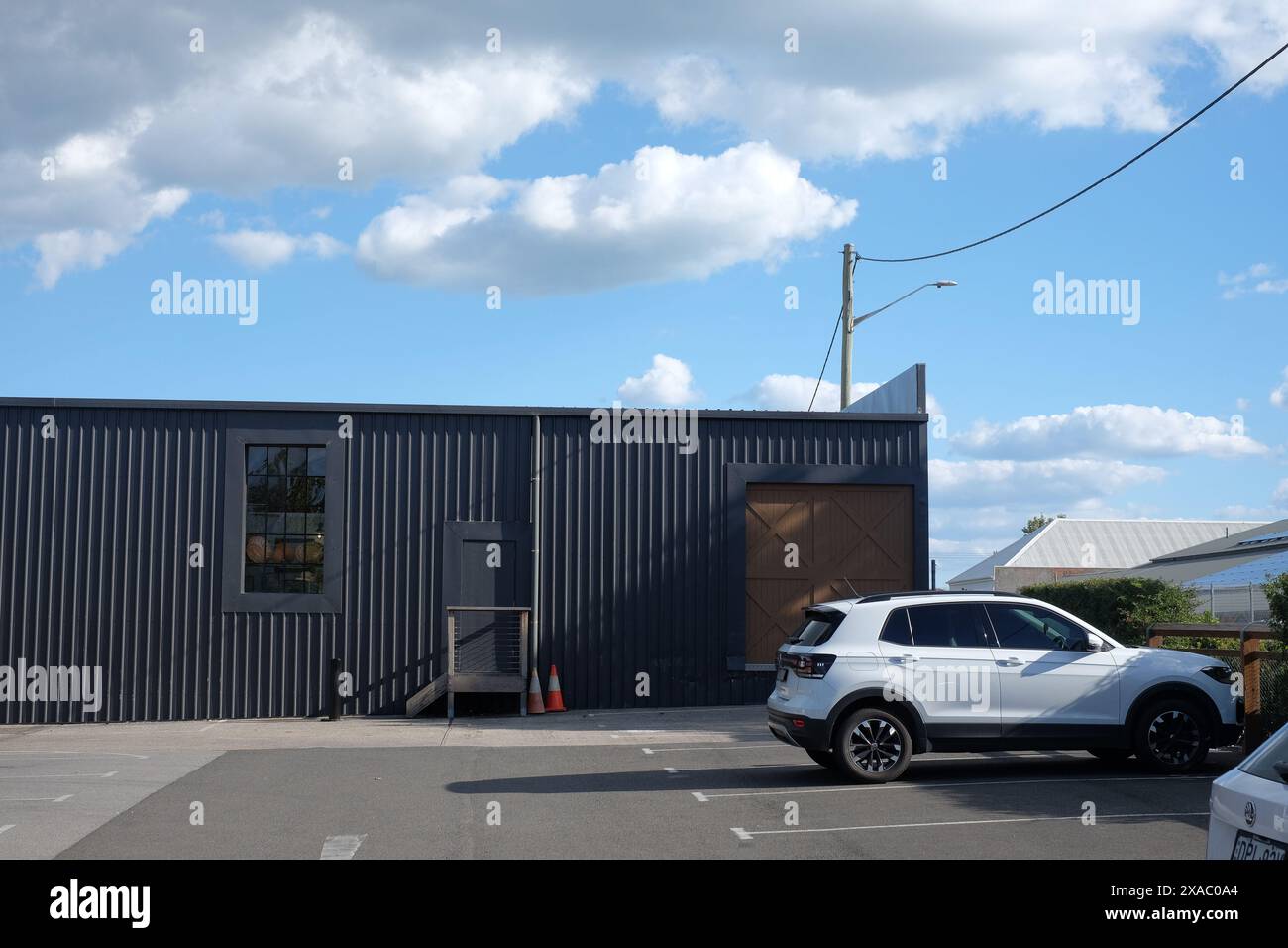 Car in a carpark, a grey warehouse wall of corrugated iron, bright blue ...