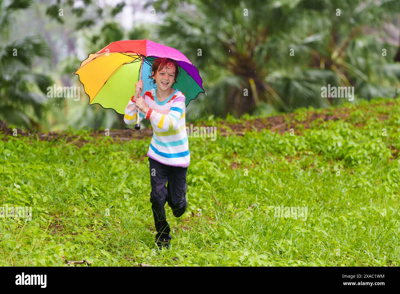 Child playing in autumn rain. Kid jumping in muddy puddle in beautiful ...