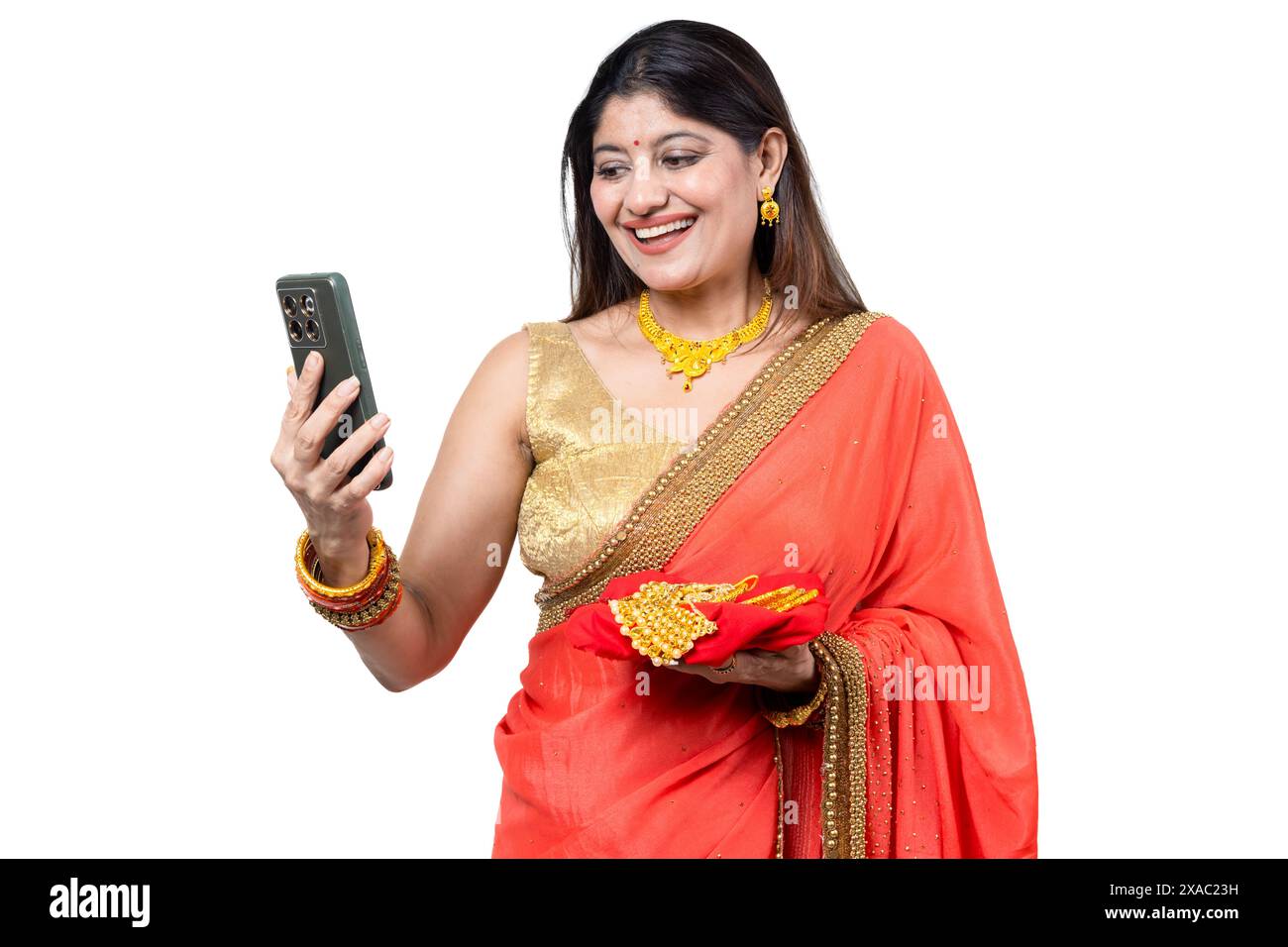 Happy young Indian woman wearing red saree holding gold jewelry ...