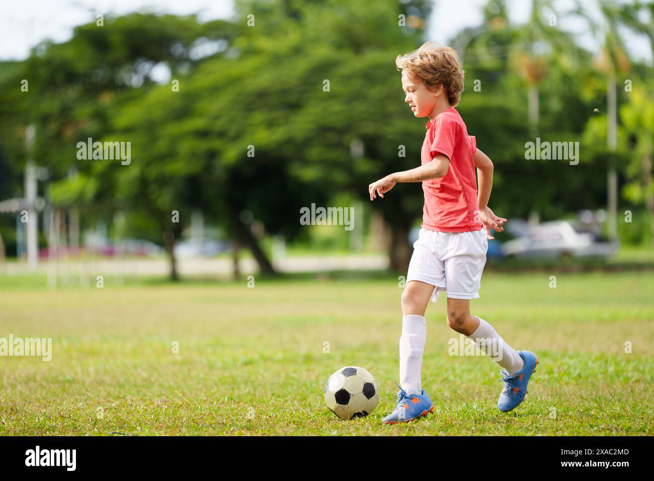 Child playing football. Kids play soccer on outdoor pitch. Little boy ...
