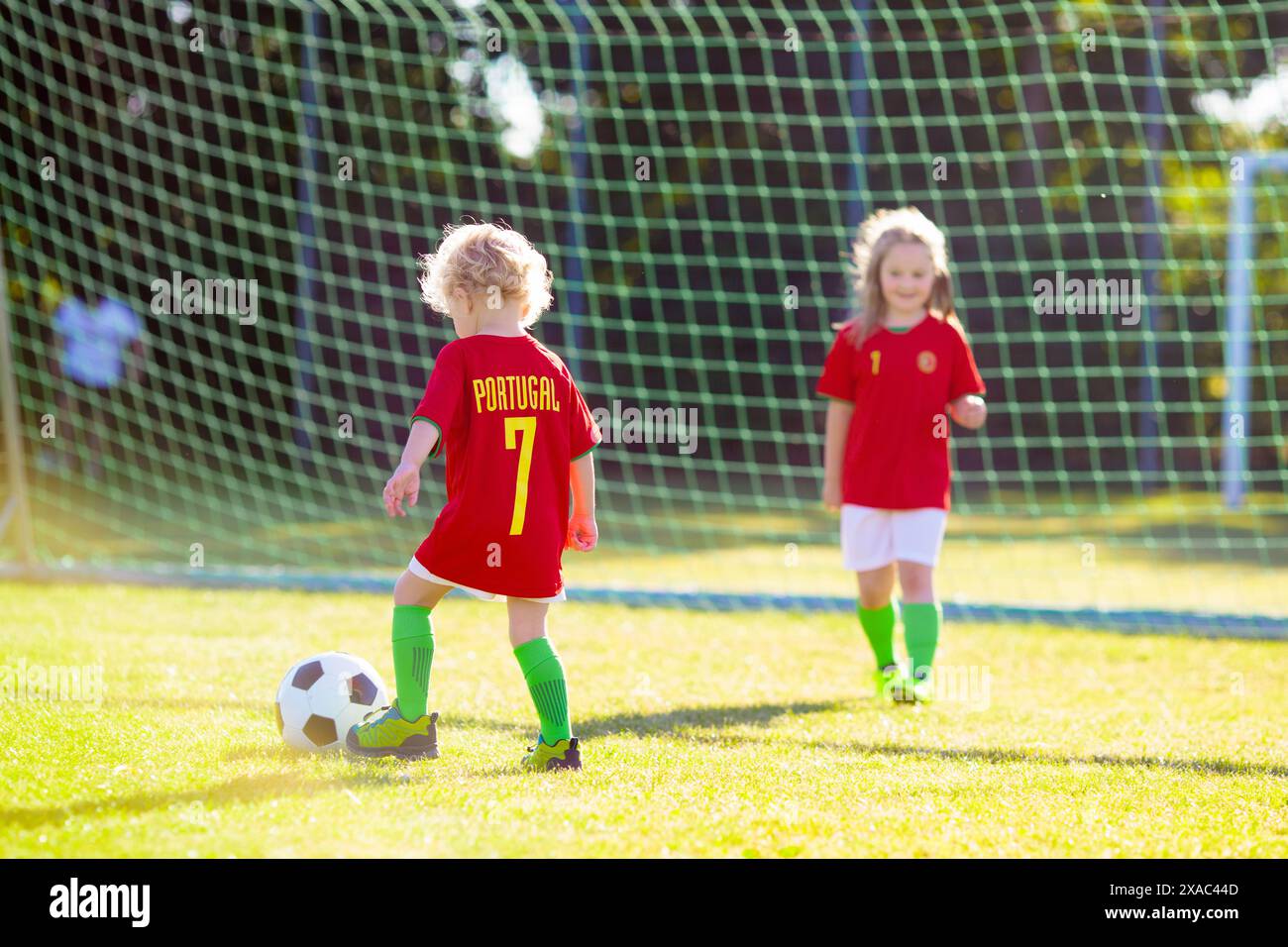 Kids play football on outdoor field. Portugal team fans. Children score ...