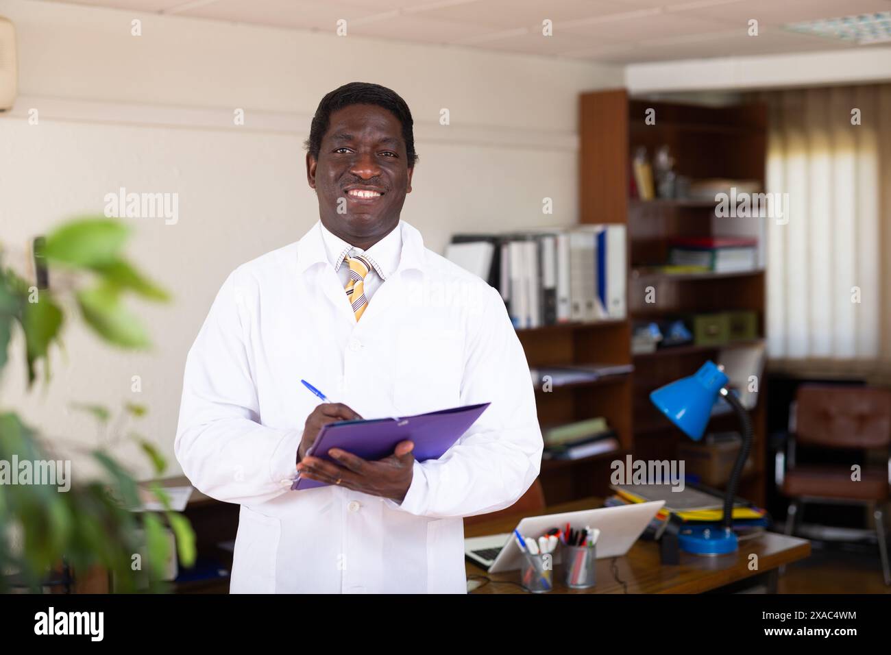 Smiling african american doctor filling out medical form in office ...