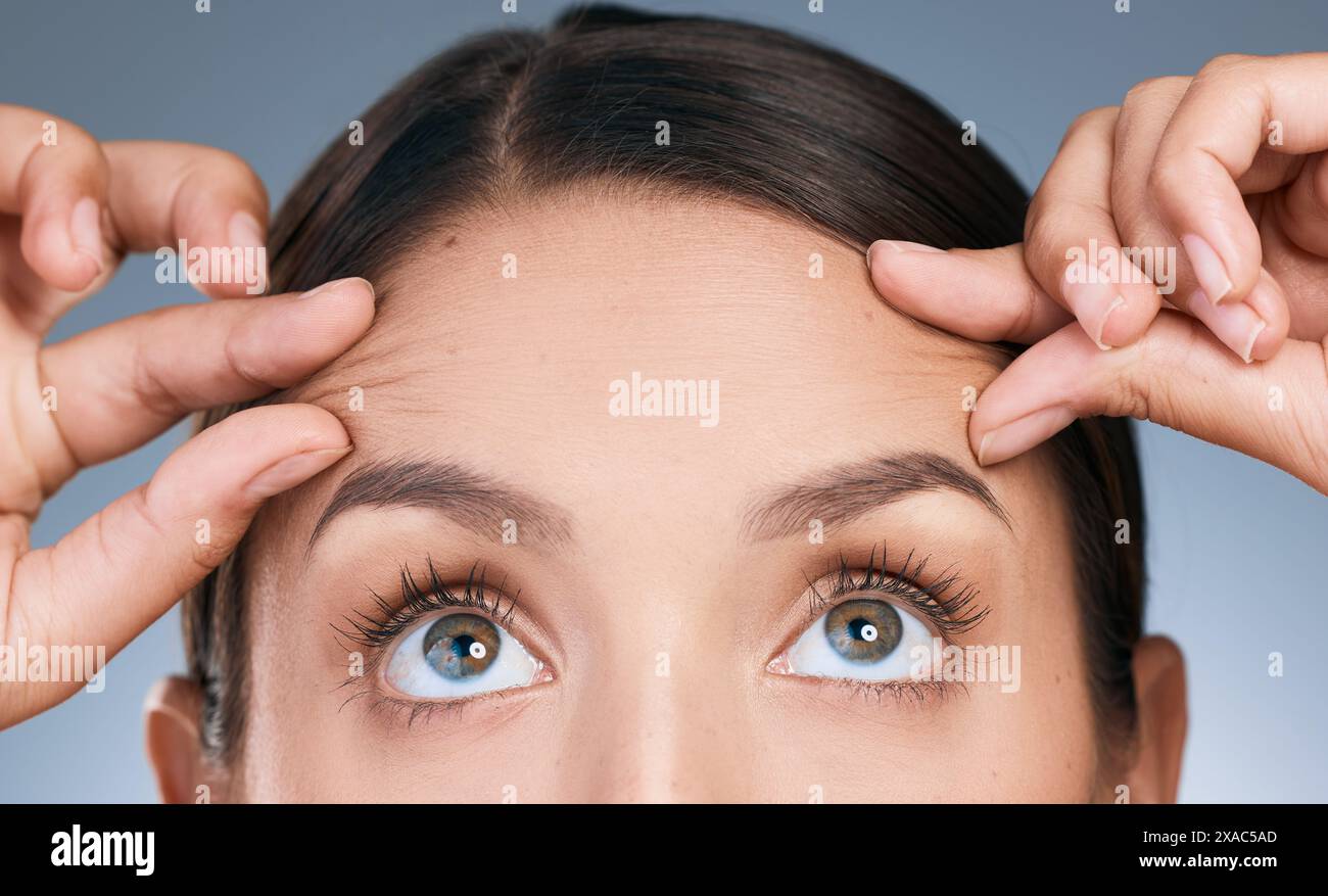 Close up, woman and hands on forehead in studio for skin care, wellness ...