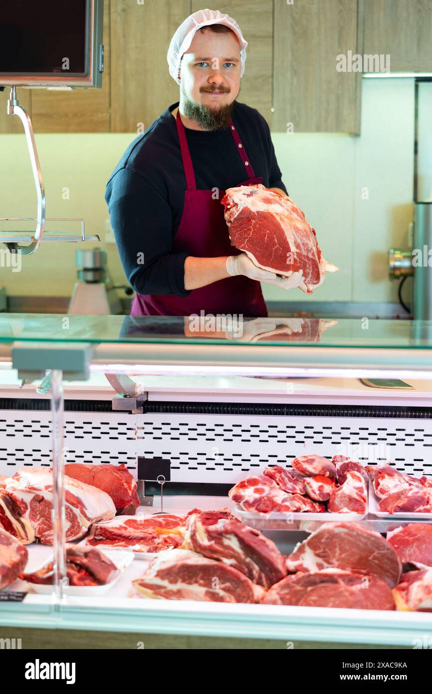 Friendly bearded butcher offering fresh beef cut Stock Photo - Alamy